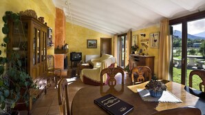 Uma sala de estar acolhedora com sofá, televisão e área de jantar com mesa e cadeiras.