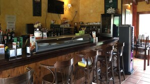 Uma área de bar com balcão, banquetas e uma vitrine.