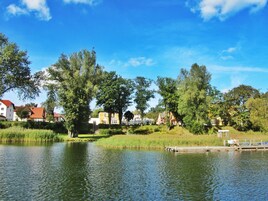 Um lago calmo com um cais e uma fileira de casas ao fundo.