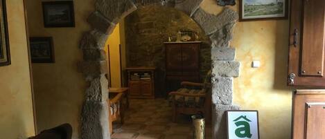 Quarto acolhedor com arco de pedra, um armário de madeira e um letreiro indicando 'Alojamiento Rural'.