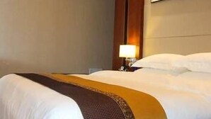 Quarto de hotel com uma cama grande, mesa de cabeceira com abajur e quadro na parede.