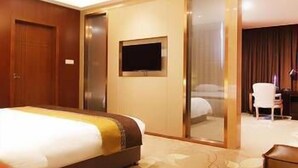 Quarto de hotel com uma cama grande, televisão, escrivaninha e uma cadeira.