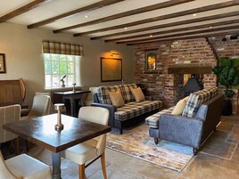 Uma sala de estar aconchegante com lareira de tijolos, um conjunto de sofás e um espaço de jantar com mesa e cadeiras.