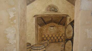 Uma adega estreita, abobadada, com barris de madeira e parede de pedra.