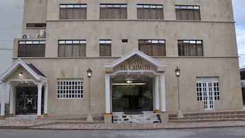 Um hotel de vários andares com uma entrada imponente, grandes janelas e uma placa com a inscrição "HOTEL EL CAIMITO".