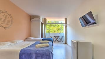Quarto de hotel com duas camas, televisão e varanda com mesa e cadeiras.