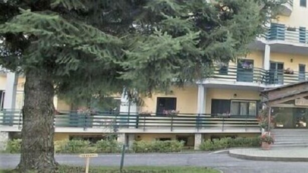 Um edifício com entrada central, área coberta com degraus e escadaria para um andar superior.