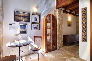 Um quarto aconchegante com um armário de madeira, uma mesa com uma cadeira e quadros nas paredes.