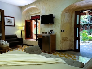 Quarto de hotel com cama, escrivaninha, televisão e vista para o exterior.