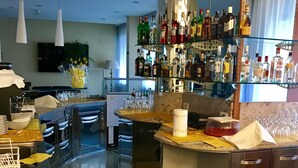 Uma cozinha moderna com ilha central, espaço bar com garrafas de bebidas e um espelho grande.