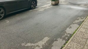 Uma área de estacionamento com um carro preto, um ônibus e um edifício com escadas.