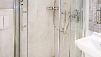 Box de chuveiro com paredes de vidro, pia branca e vaso sanitário.