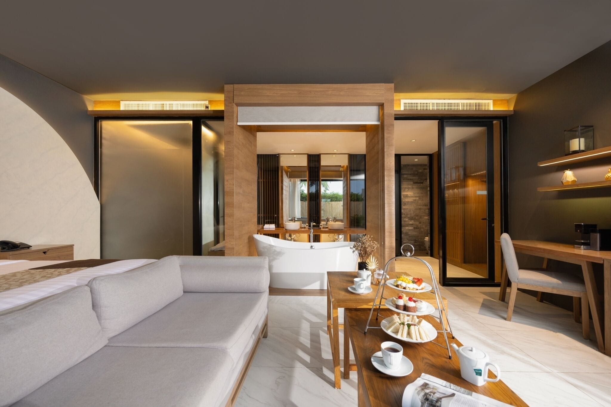 Quarto de hotel moderno com sofá, mesa de jantar com café da manhã e banheira.