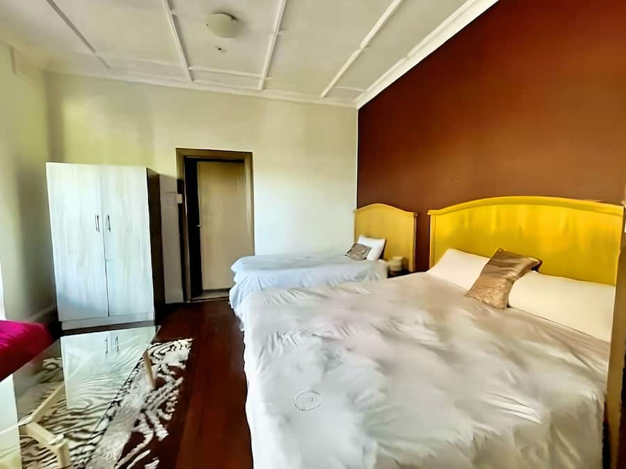 Quarto de hotel com uma cama grande, um guarda-roupa e uma porta que dá para outro cômodo.