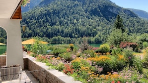 Varanda com vista para uma paisagem montanhosa e um jardim com diversas flores.