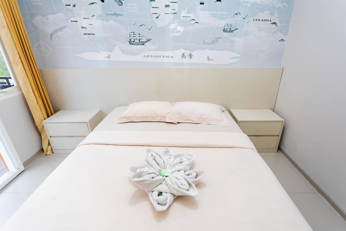 Quarto de hotel com uma cama, um mapa na parede e uma escultura de toalha na cama.