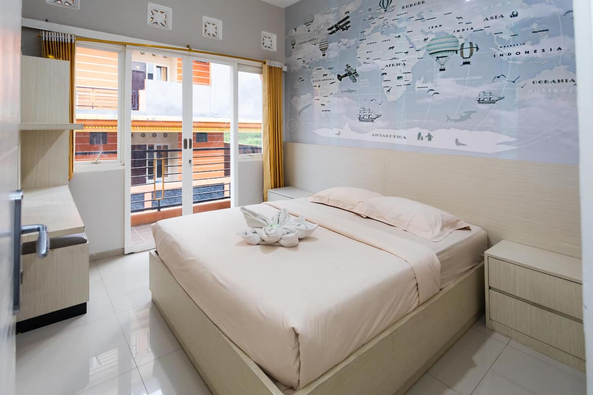 Quarto de hotel com cama, mesa de cabeceira, guarda-roupa e janela com vista para uma varanda.