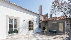 Um pátio com um edifício branco, telhado em azulejos e uma banheira verde.