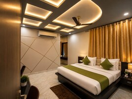 Quarto moderno com cama, mesas de cabeceira, ar-condicionado e ventilador de teto.
