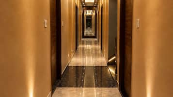 Corredor longo em um hotel, com portas de ambos os lados e piso de mármore.