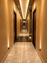 Corredor longo em um hotel, com portas de ambos os lados e piso de mármore.