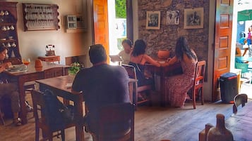 Um restaurante com mesas e cadeiras de madeira, uma parede de pedra e algumas fotos emolduradas na parede.
