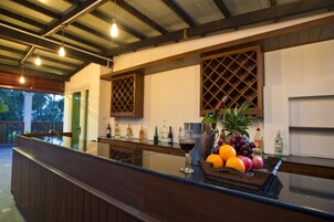 Uma área de bar com balcão, garrafas, copos e frutas.