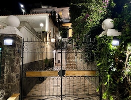 Uma entrada com portão e um caminho de azulejos que leva a um edifício com varanda.