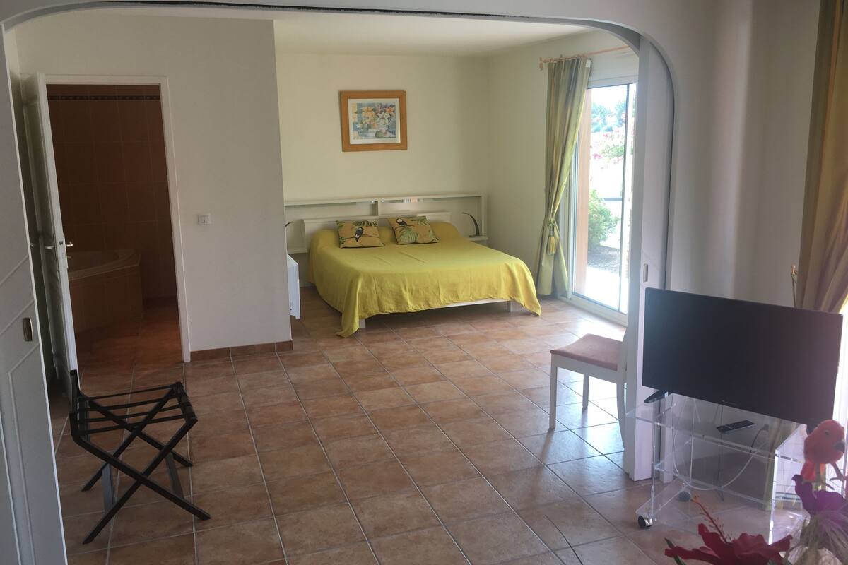 Quarto com cama, poltrona, televisão e um quadro na parede.