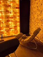 Um espaço de spa com uma cadeira de massagem, uma mesa pequena e uma parede texturizada.