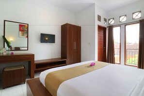 Quarto de hotel com cama, escrivaninha com espelho, televisão e guarda-roupa.