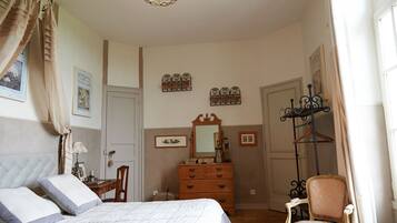 Quarto com cama, penteadeira, cadeira e espelho.