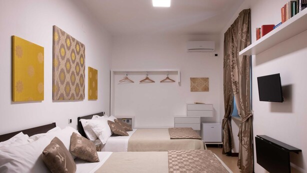 Quarto de hotel com duas camas, uma televisão de tela plana, um guarda-roupa e uma escrivaninha.