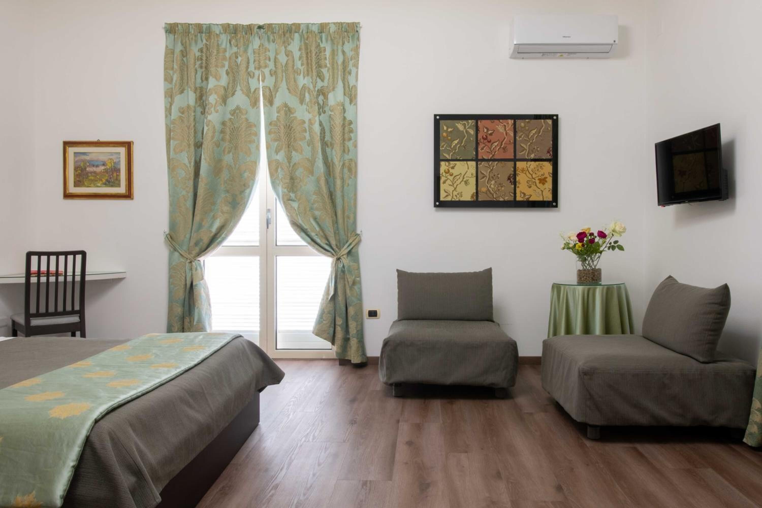 Quarto com duas camas, uma escrivaninha, televisão e janela com cortinas.