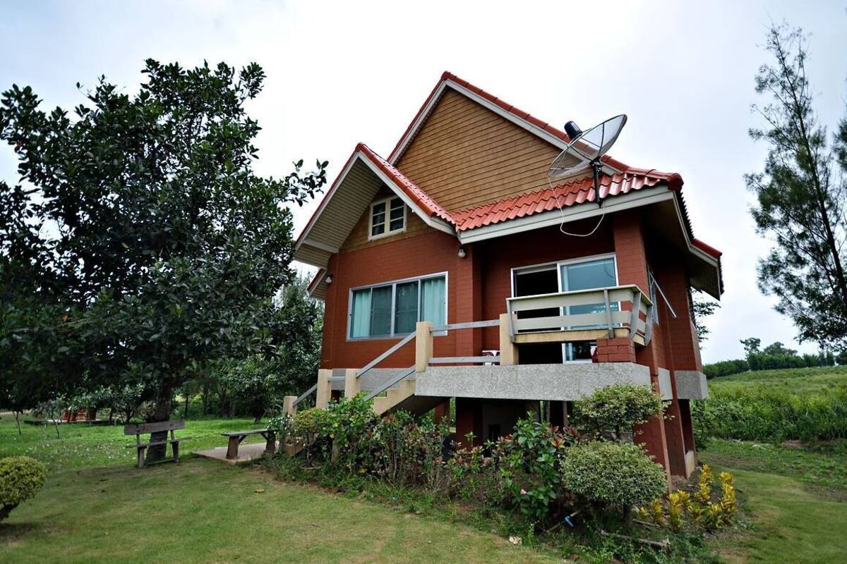 Uma casa de dois andares com telhado vermelho e uma antena parabólica.