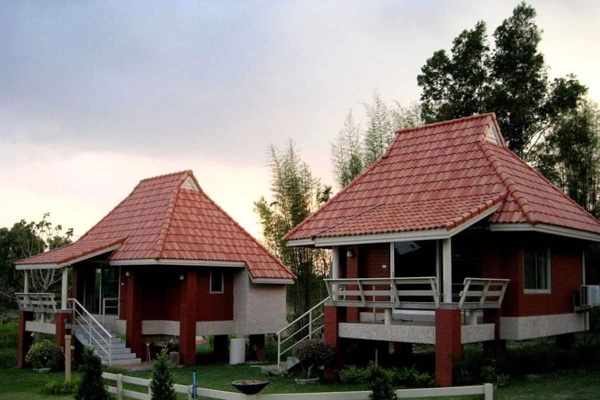 Duas casas de campo com telhados vermelhos, grades brancas e uma cerca branca à frente.