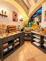Uma mesa de buffet com pães, doces e diversos pratos.