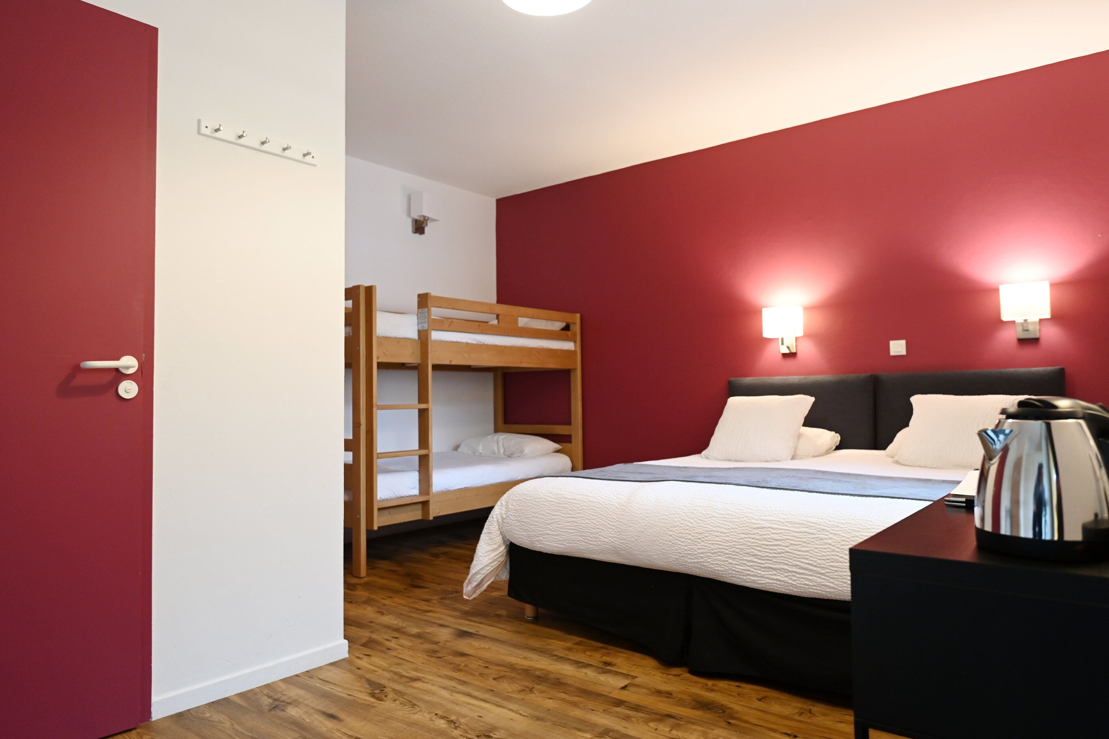 Quarto com cama beliche, escrivaninha com chaleira e duas luminárias.