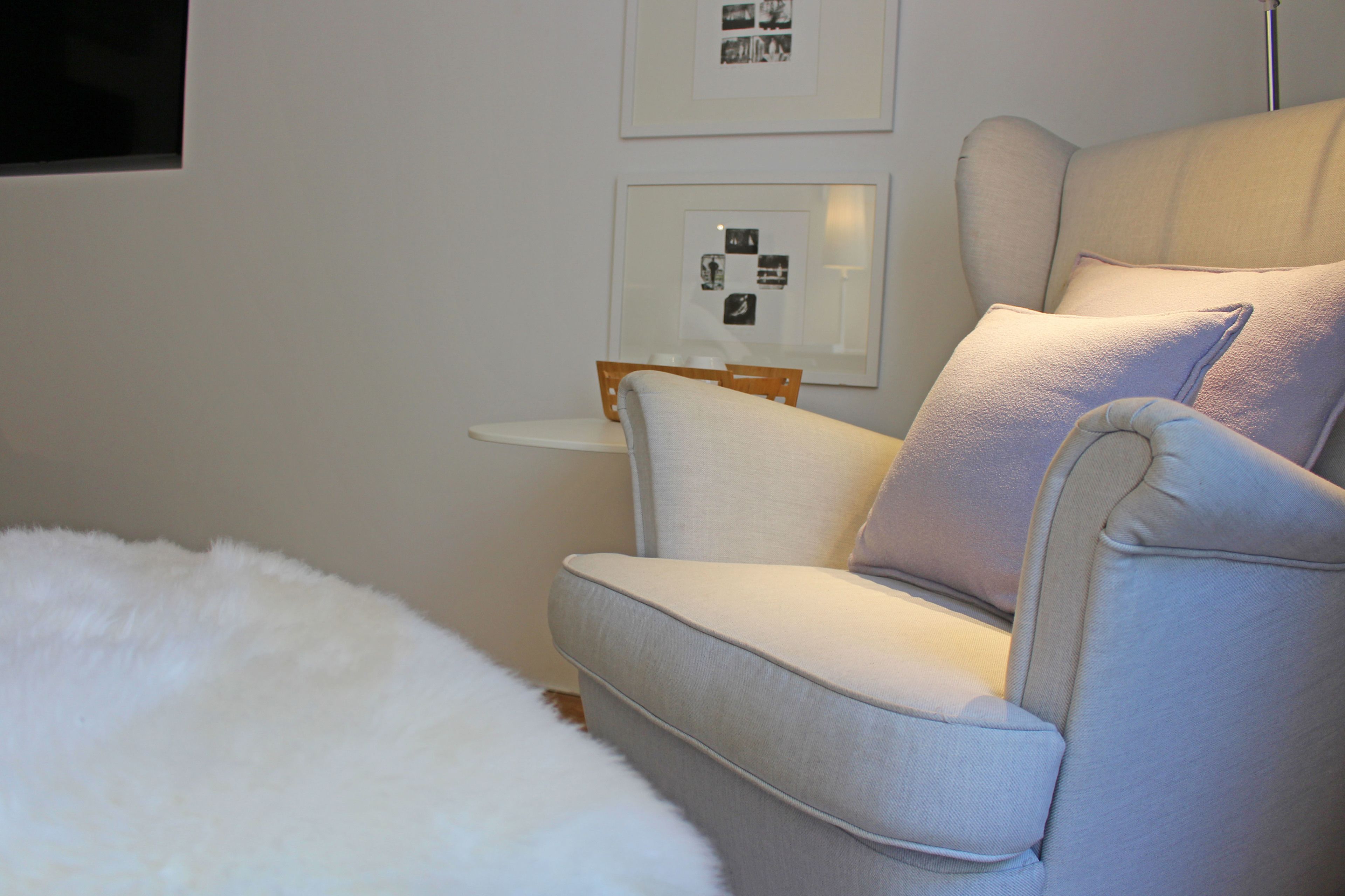Uma sala de estar moderna com um sofá branco macio, uma mesa redonda pequena e quadros na parede.