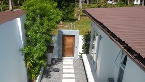Uma casa moderna com piscina, porta de madeira e um pequeno jardim com palmeiras.