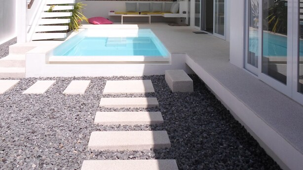 Uma casa moderna com piscina, escadaria e porta de vidro que dá para uma varanda.