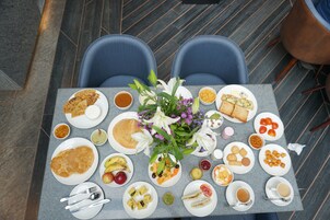 Uma mesa de jantar com diversos pratos, incluindo panquecas, frutas e um arranjo floral.