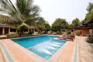 Piscina com espreguiçadeiras e palmeiras.