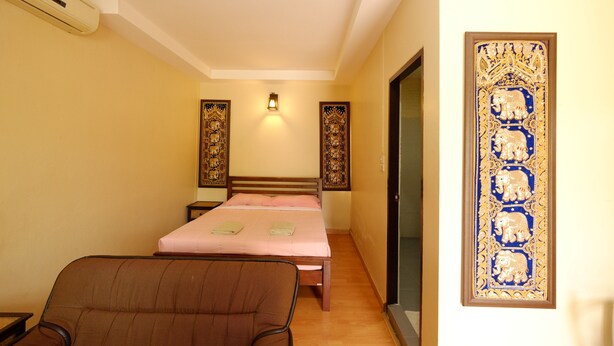 Quarto de hotel com uma cama, uma cadeira, ar condicionado fixado na parede e painéis decorativos.
