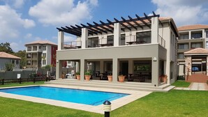 Um edifício moderno de dois andares com área de estar coberta ao ar livre e piscina.