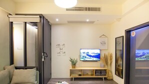 Uma sala de estar moderna com um sofá, uma TV, uma estante e uma porta de correr.