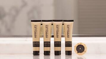 Quatro embalagens de produtos de cuidados para a pele APPELLLES sobre uma superfície reflexiva.