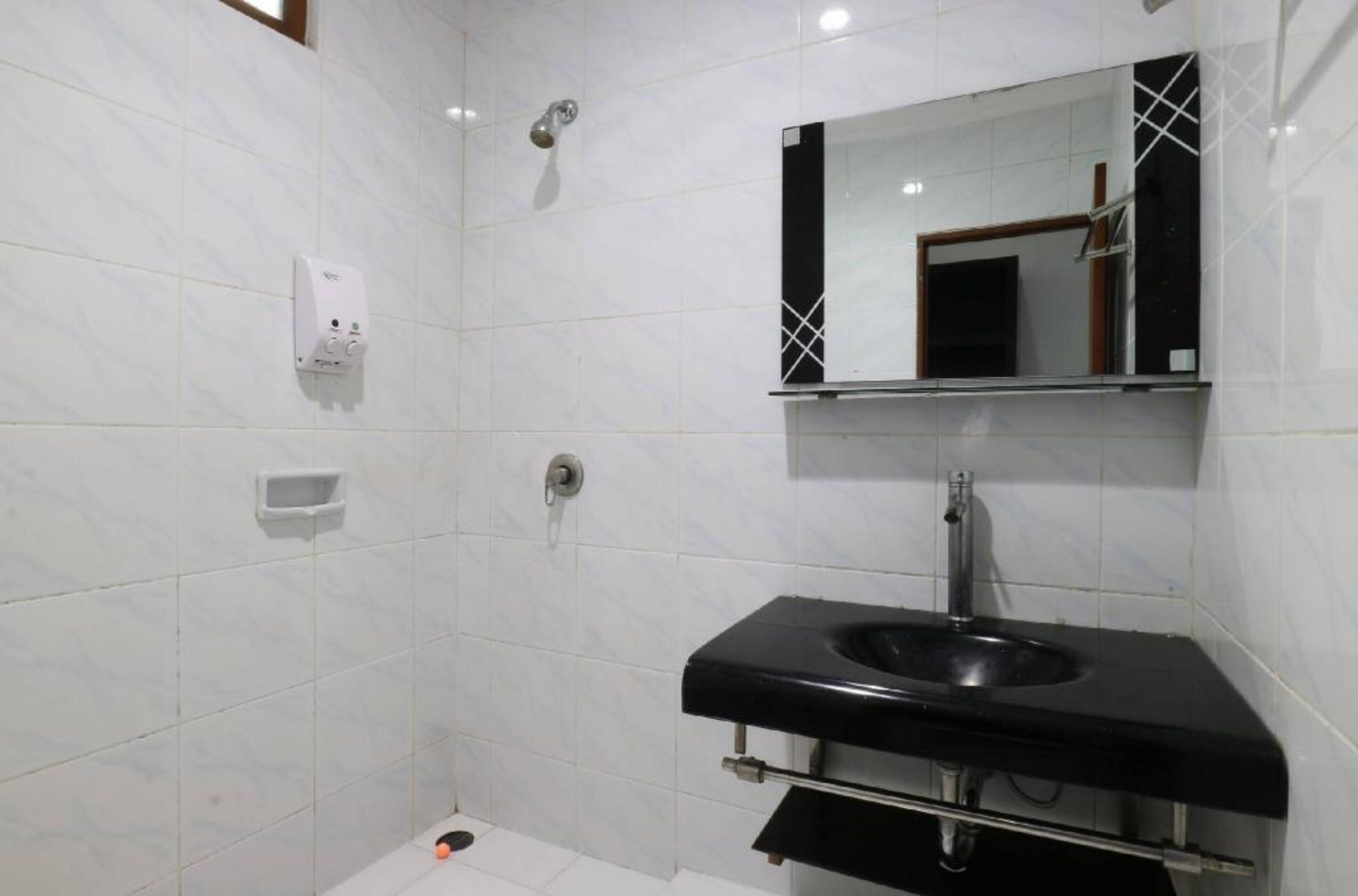 Casa de banho com lavatório preto, espelho e secador de mãos.