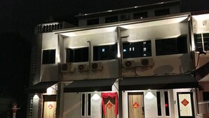 Um edifício de dois andares com várias unidades de ar condicionado, entrada com portão e fachada bem iluminada.