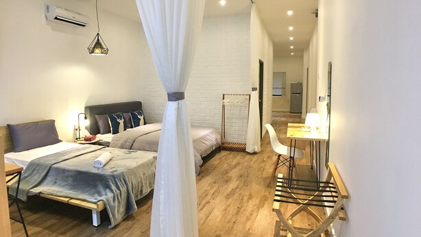 Quarto de hotel moderno com cama, mesa de cabeceira, abajur e pequena escrivaninha com cadeira.